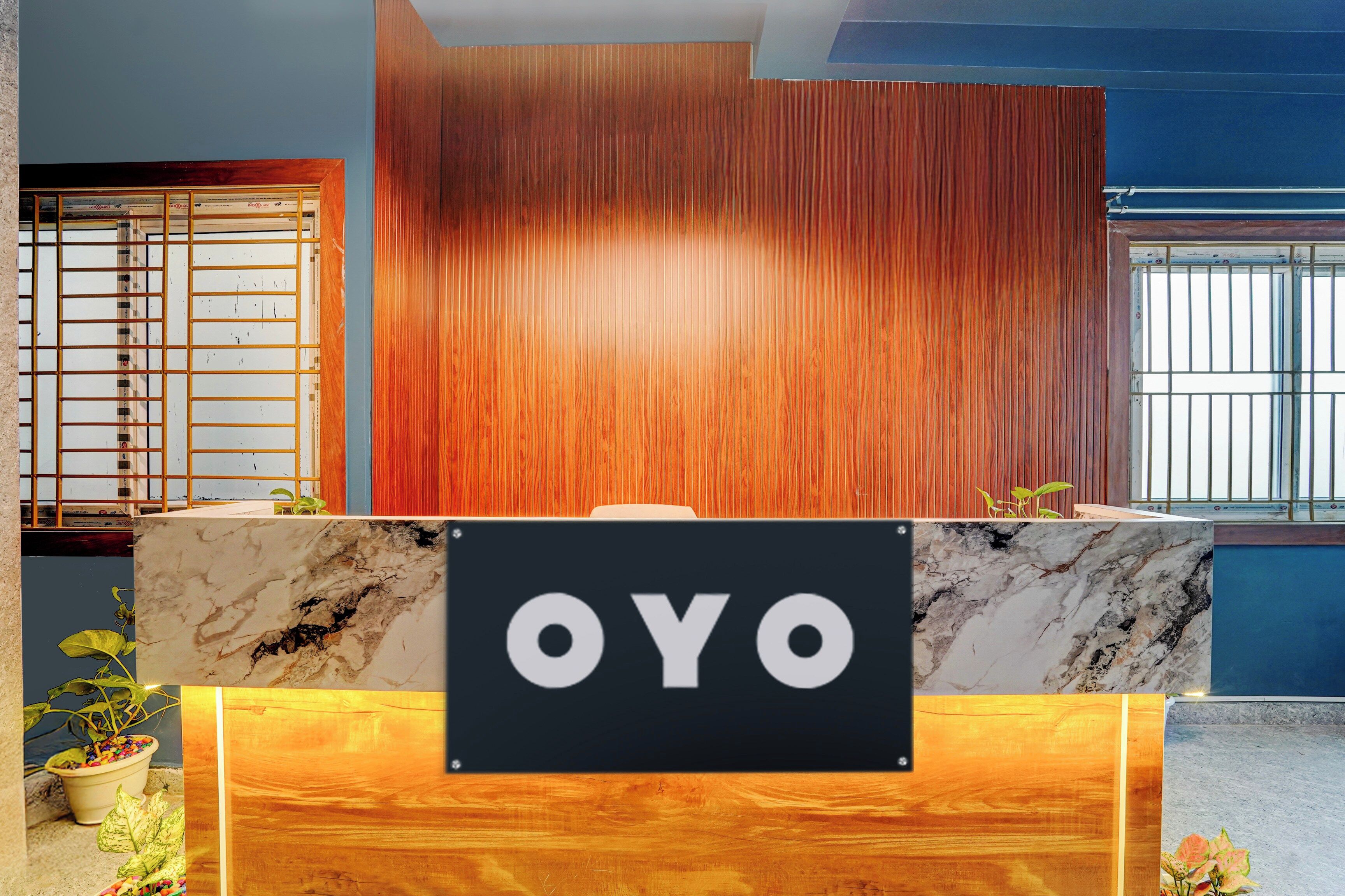 Balcão de recepção com uma placa indicando 'OYO' em um interior moderno com lambris de madeira e detalhes em mármore.