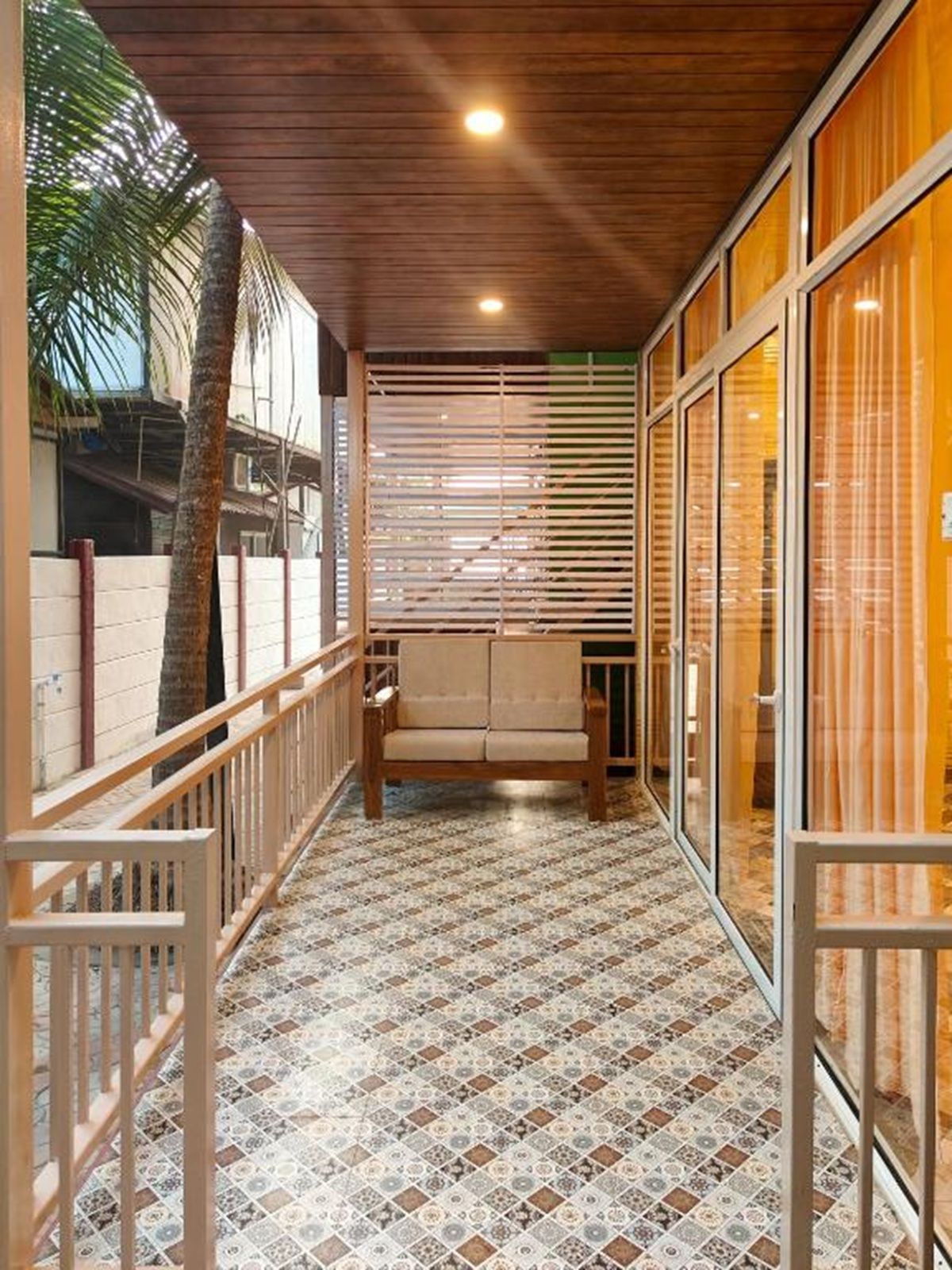 Um corredor com piso estampado, um banco de madeira e uma porta de vidro.