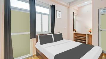 Quarto com cama, janela com cortinas, mesa de cabeceira com um vaso de flores e guarda-roupa.