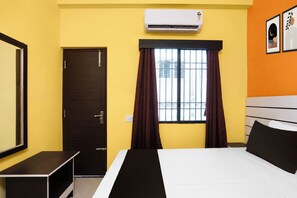 Quarto de hotel com cama, janela com cortinas, aparelho de ar condicionado e porta.