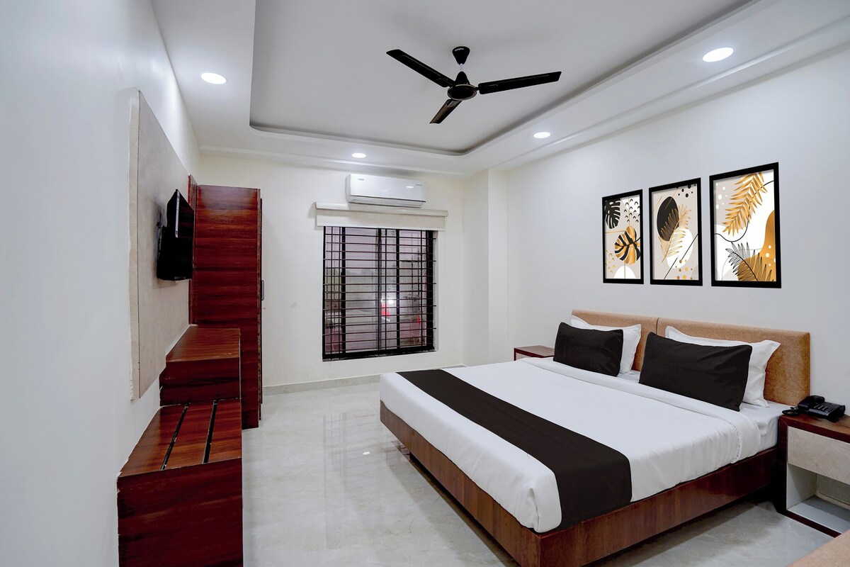 Quarto de hotel com cama, mesa de cabeceira e ventoinha no teto.