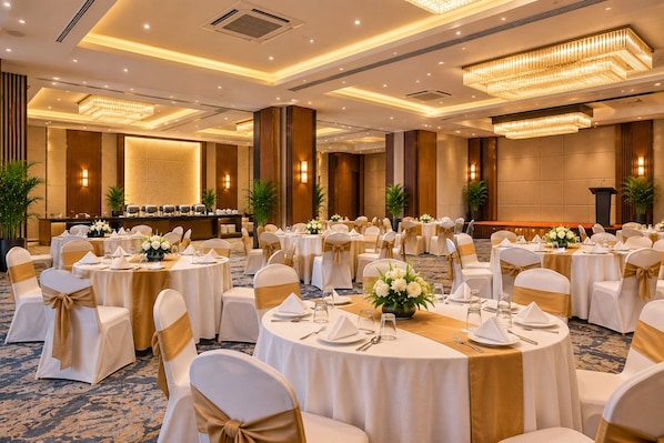 Uma sala de banquetes com mesas redondas, cadeiras e um palco.