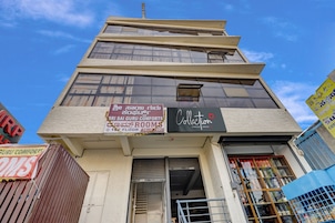 Um edifício de vários andares com sinalização indicando 'SRI SAI GURU COMFORTS' e 'Collection' no andar térreo.