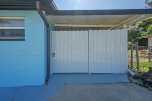 Garagem com porta branca, entrada coberta e fachada azul.