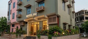 Um edifício de hotel com vários andares e uma placa com a inscrição 'HOTEL JAI PREMIUM ACCOMMODATION'.