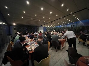 Um espaço de refeições interno movimentado, com mesas e cadeiras dispostas para os hóspedes.