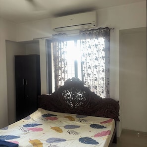 Quarto com cama, guarda-roupa e ar condicionado.