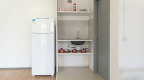 Cozinha compacta com geladeira branca, pia e bancada com panelas.