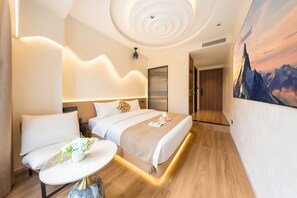 Quarto de hotel moderno com cama, mesa de cabeceira e um quadro na parede.