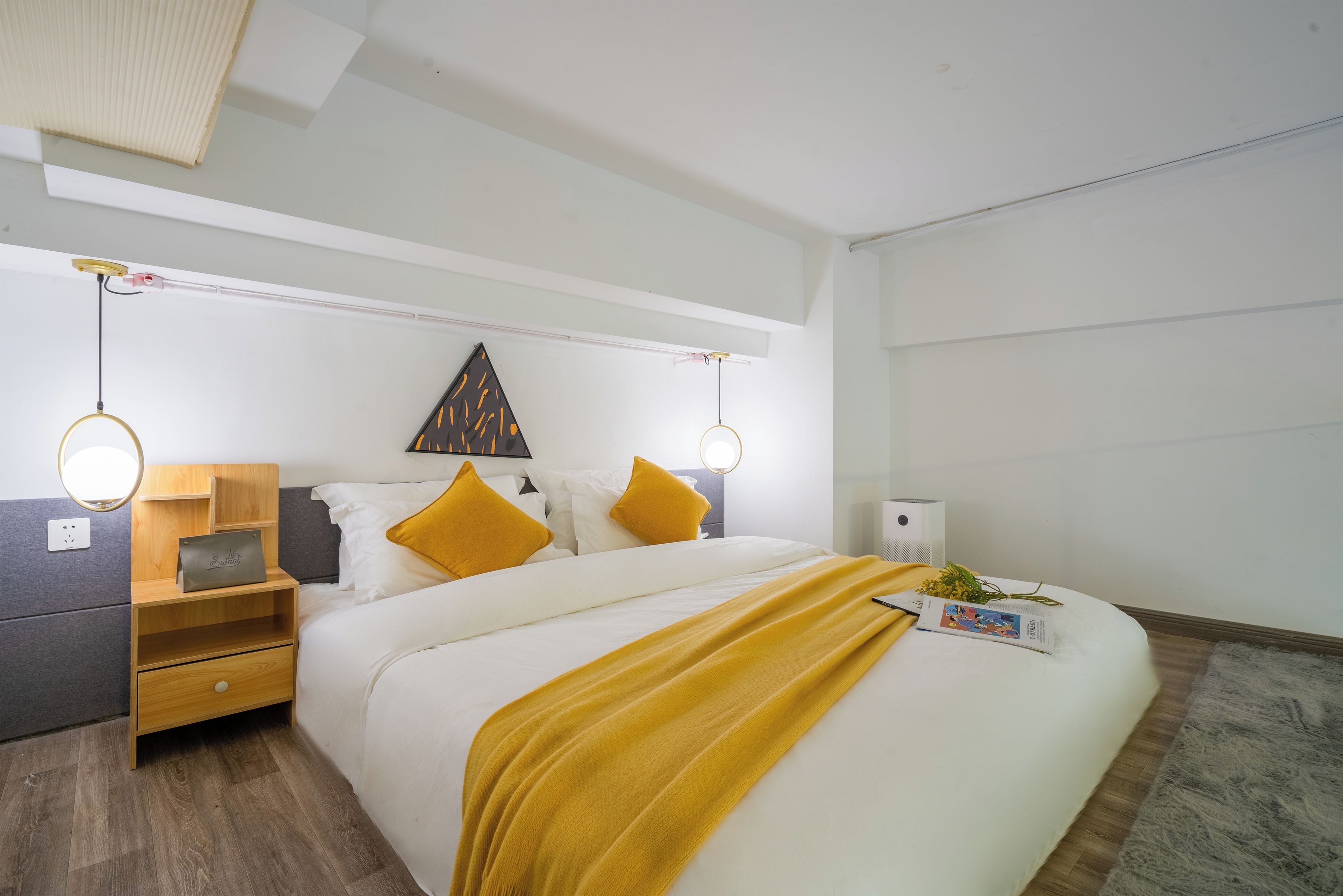 Quarto de hotel com cama, mesas de cabeceira, escrivaninha e luminária.
