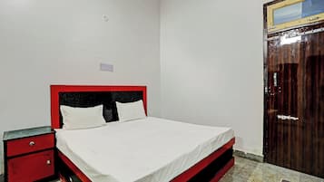 Quarto com uma cama de solteiro, mesa de cabeceira, guarda-roupa e espelho.