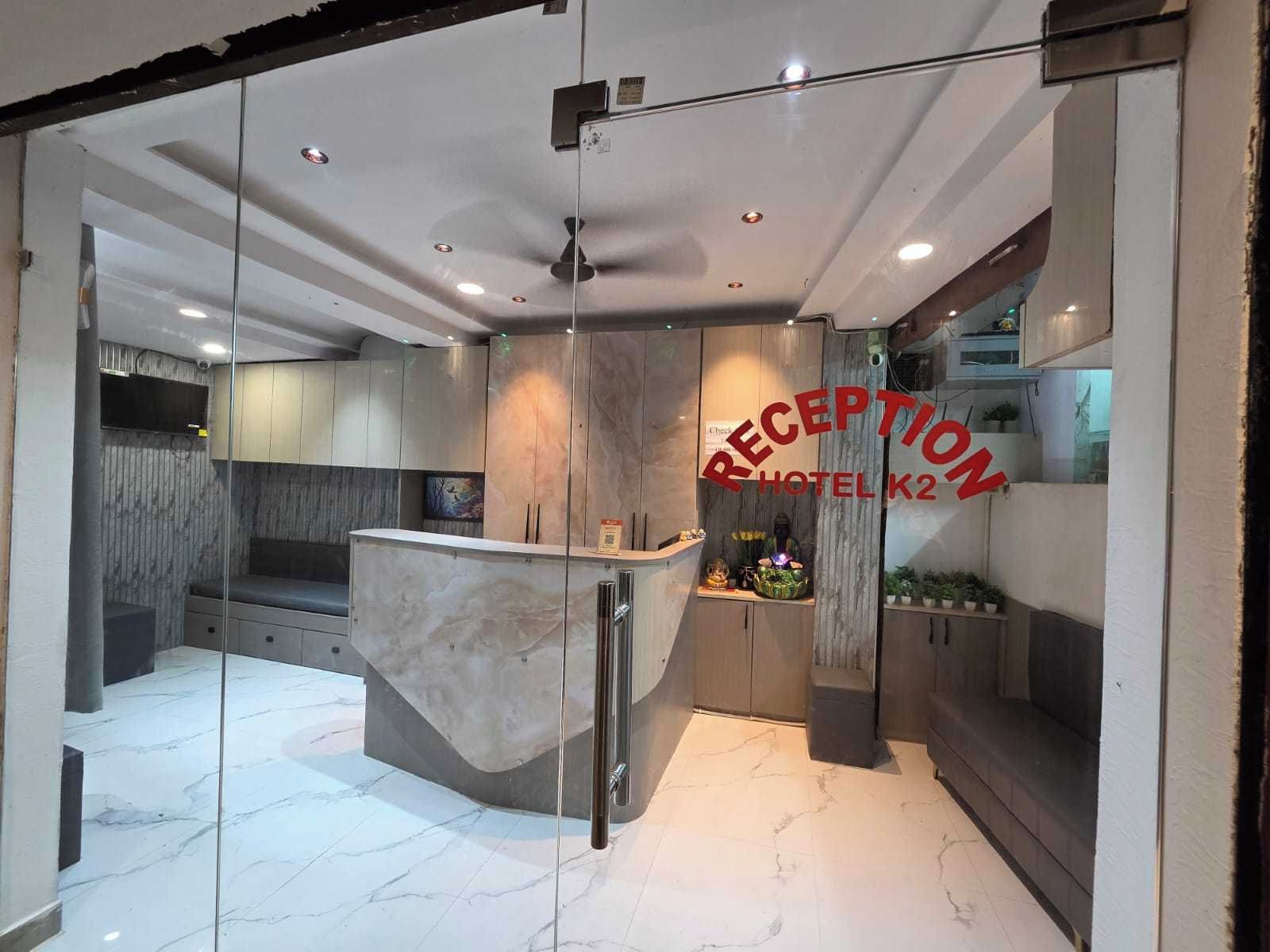 Uma área de recepção de hotel moderna, com balcão de mármore, divisórias de vidro e design minimalista.