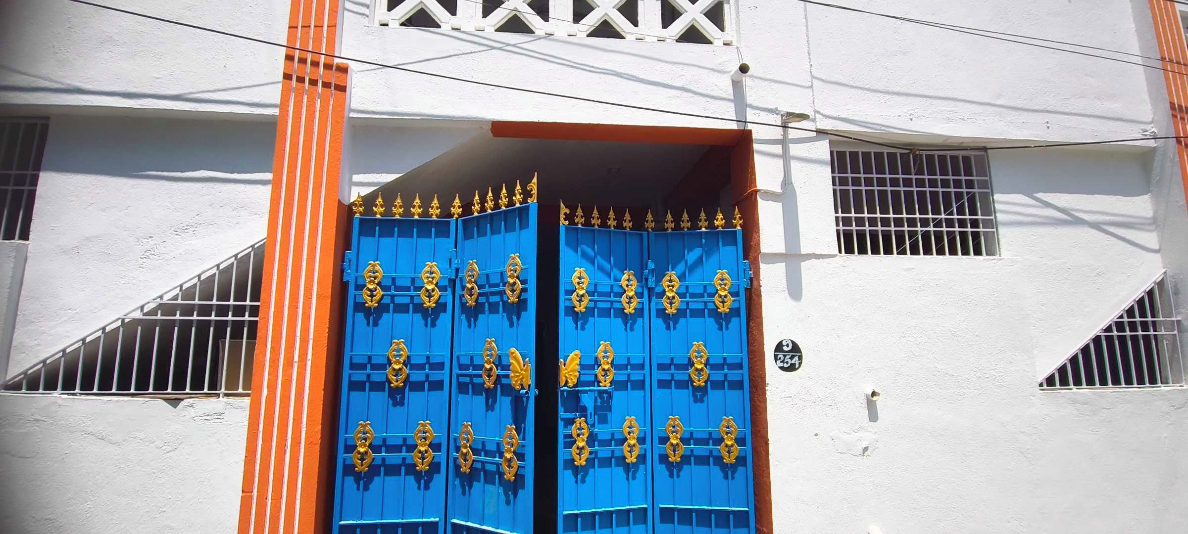 Um edifício com fachada branca, porta azul e puxadores dourados, e uma placa com o número 254.