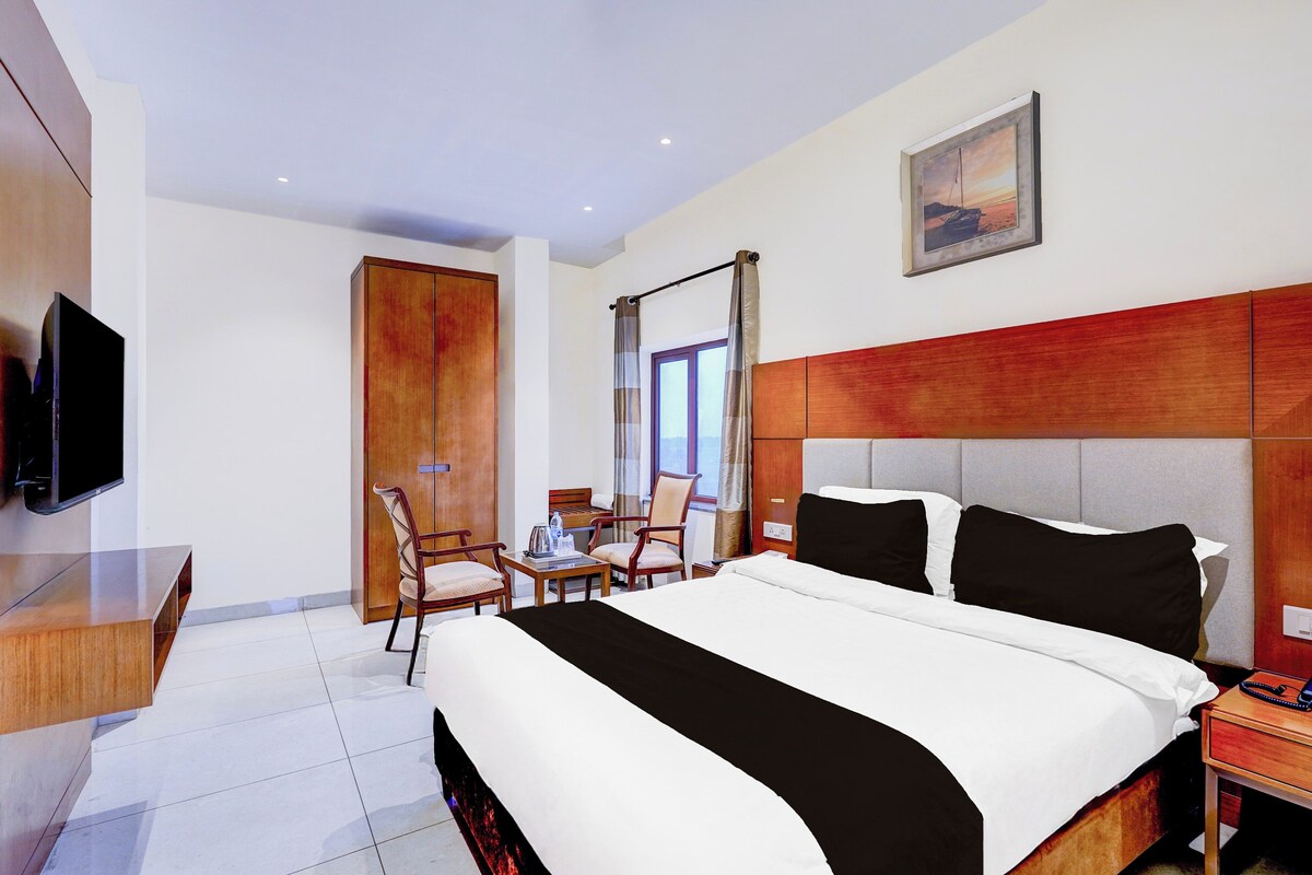 Quarto de hotel com uma cama grande, televisão, escrivaninha e uma cadeira.