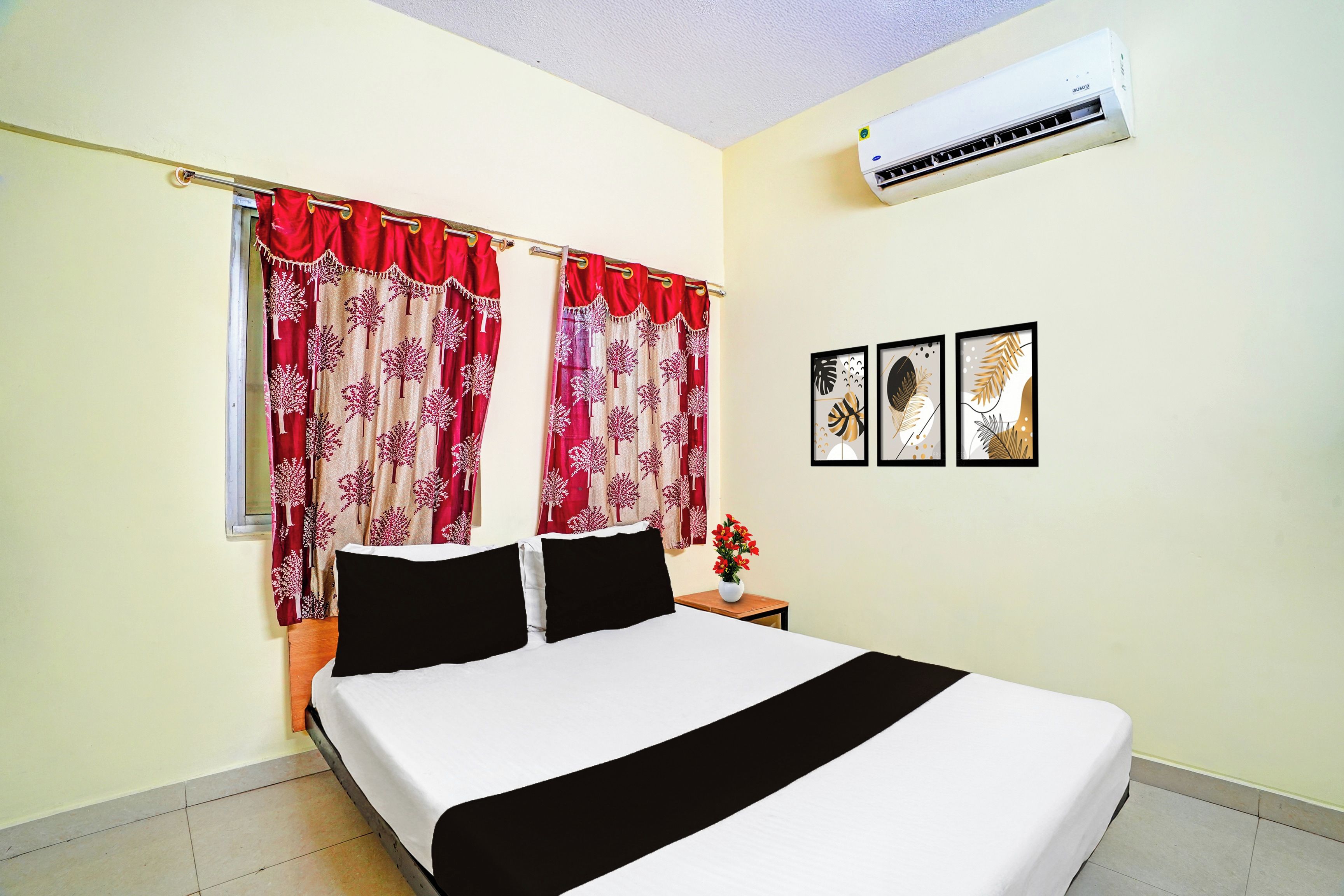 Quarto com cama, cortinas, ar condicionado e obras de arte nas paredes.