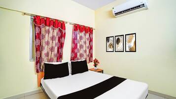 Quarto com cama, cortinas, ar condicionado e obras de arte nas paredes.