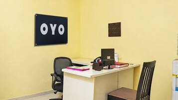 Um quarto com escrivaninha, cadeira, computador e uma placa com a inscrição 'OYO'.