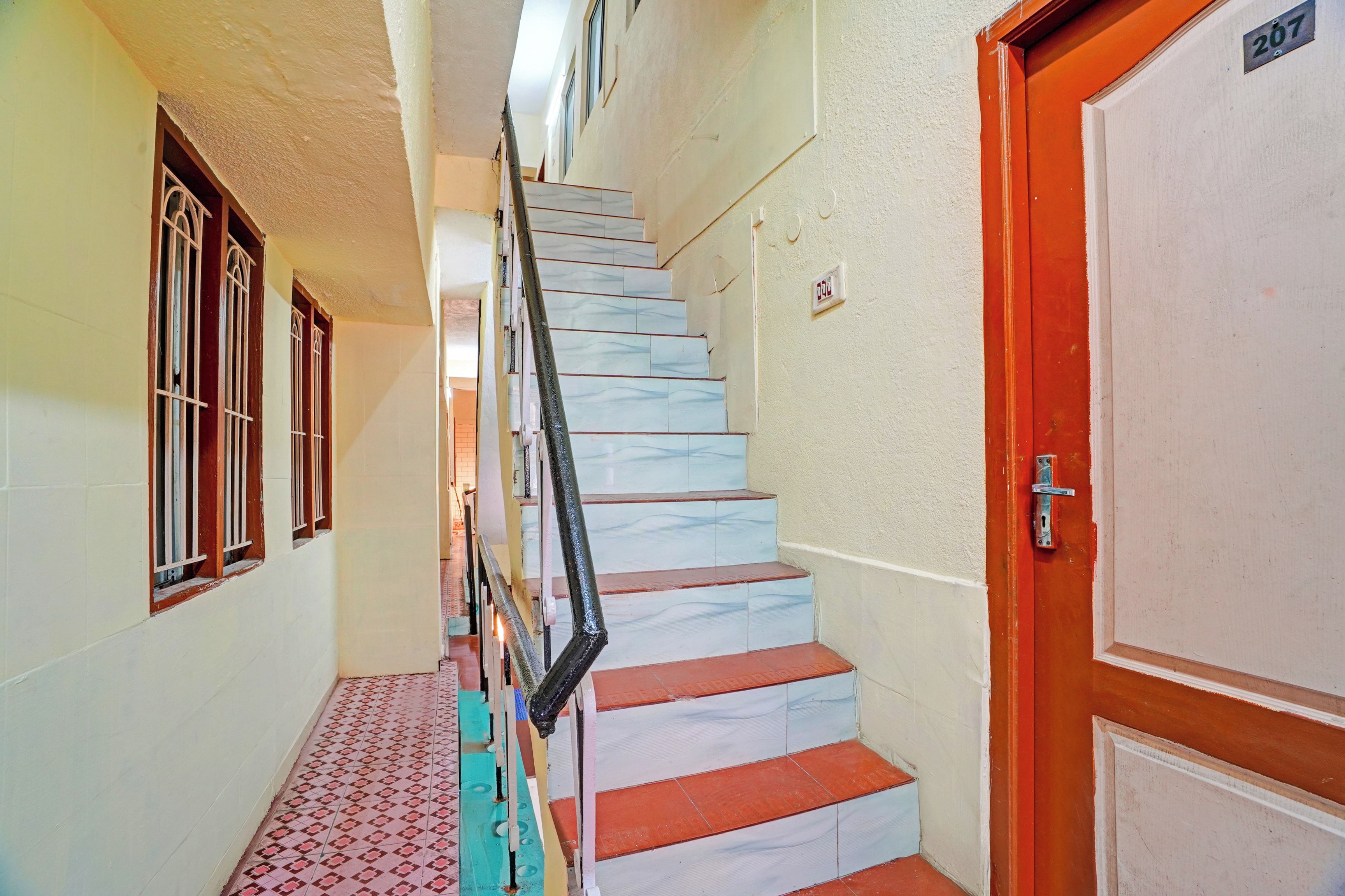 Um corredor estreito com escadas que levam a uma porta com o número 207.
