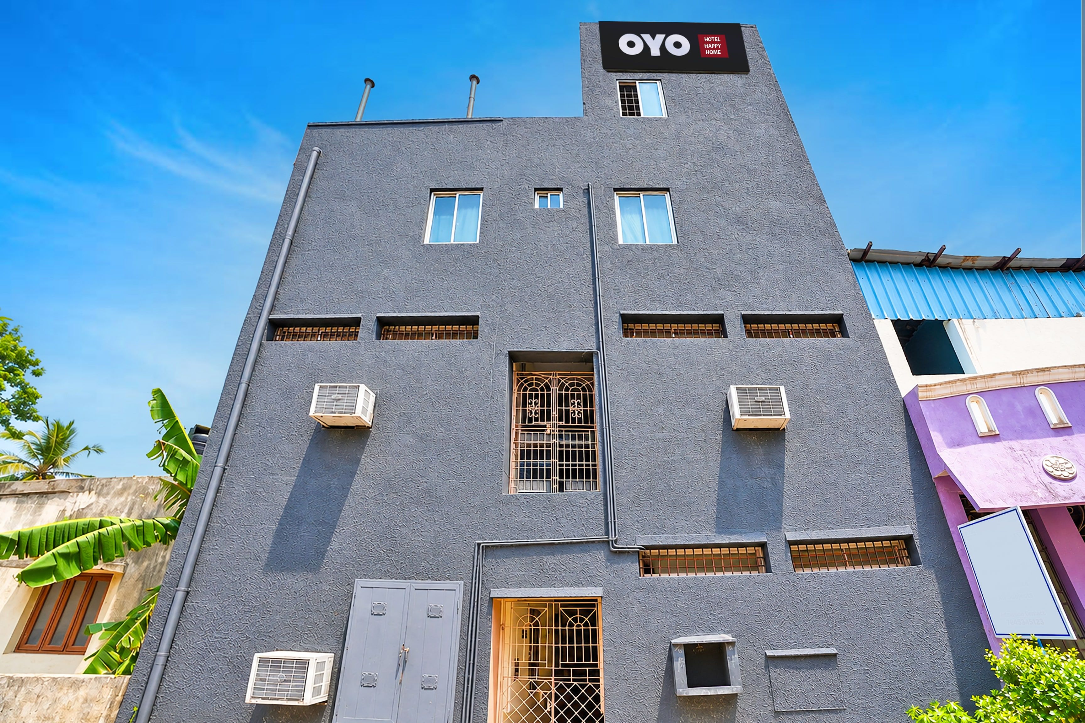 Um edifício com uma placa indicando 'OYO HOTEL HAPPY HOME' no topo.