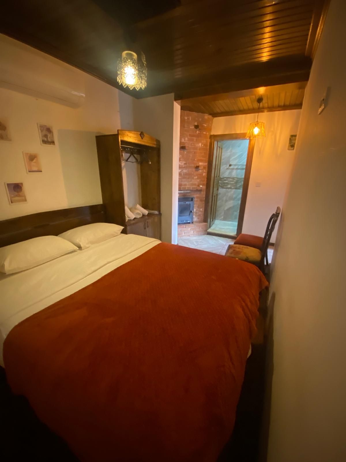Quarto de hotel com uma cama grande, cabeceira de madeira, guarda-roupa e varanda com vista.