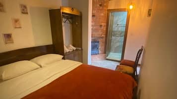 Quarto de hotel com uma cama grande, cabeceira de madeira, guarda-roupa e varanda com vista.