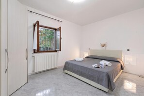 Quarto com cama, janela, radiador e luz acoplada à parede.
