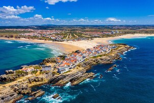 Uma vila costeira com praia, costa rochosa e edifícios com telhados vermelhos.