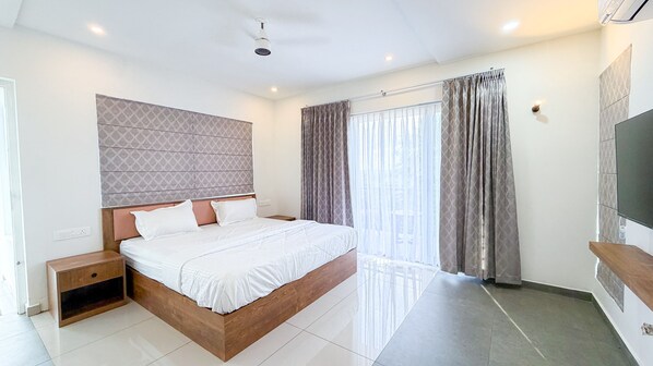 Quarto de hotel moderno com uma cama grande, televisão de tela plana e vista para o exterior.