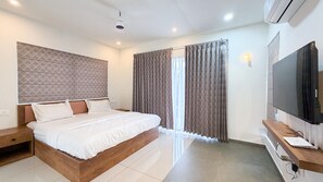 Quarto de hotel moderno com uma cama grande, TV de tela plana e porta de vidro deslizante que dá para uma varanda.