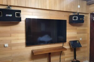 Televisão de tela plana fixada em parede de madeira, com um banco abaixo.