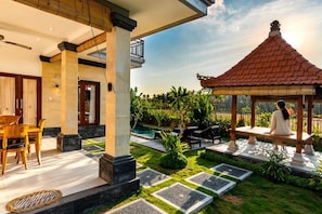 Uma área externa coberta com um banco, piscina e um gazebo.