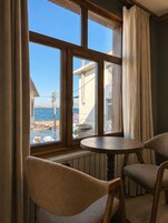 Quarto com vista para o mar, uma mesa e duas cadeiras.