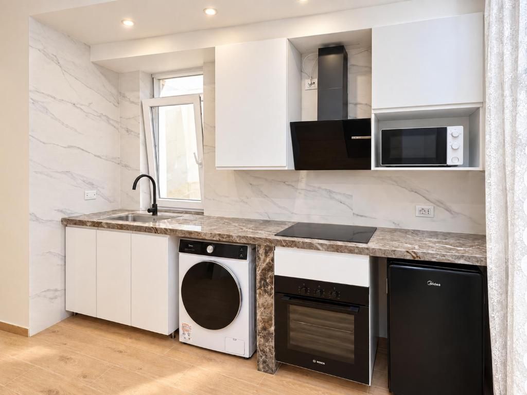 Cozinha moderna equipada com máquina de lavar roupa, máquina de lavar loiça, forno e micro-ondas.