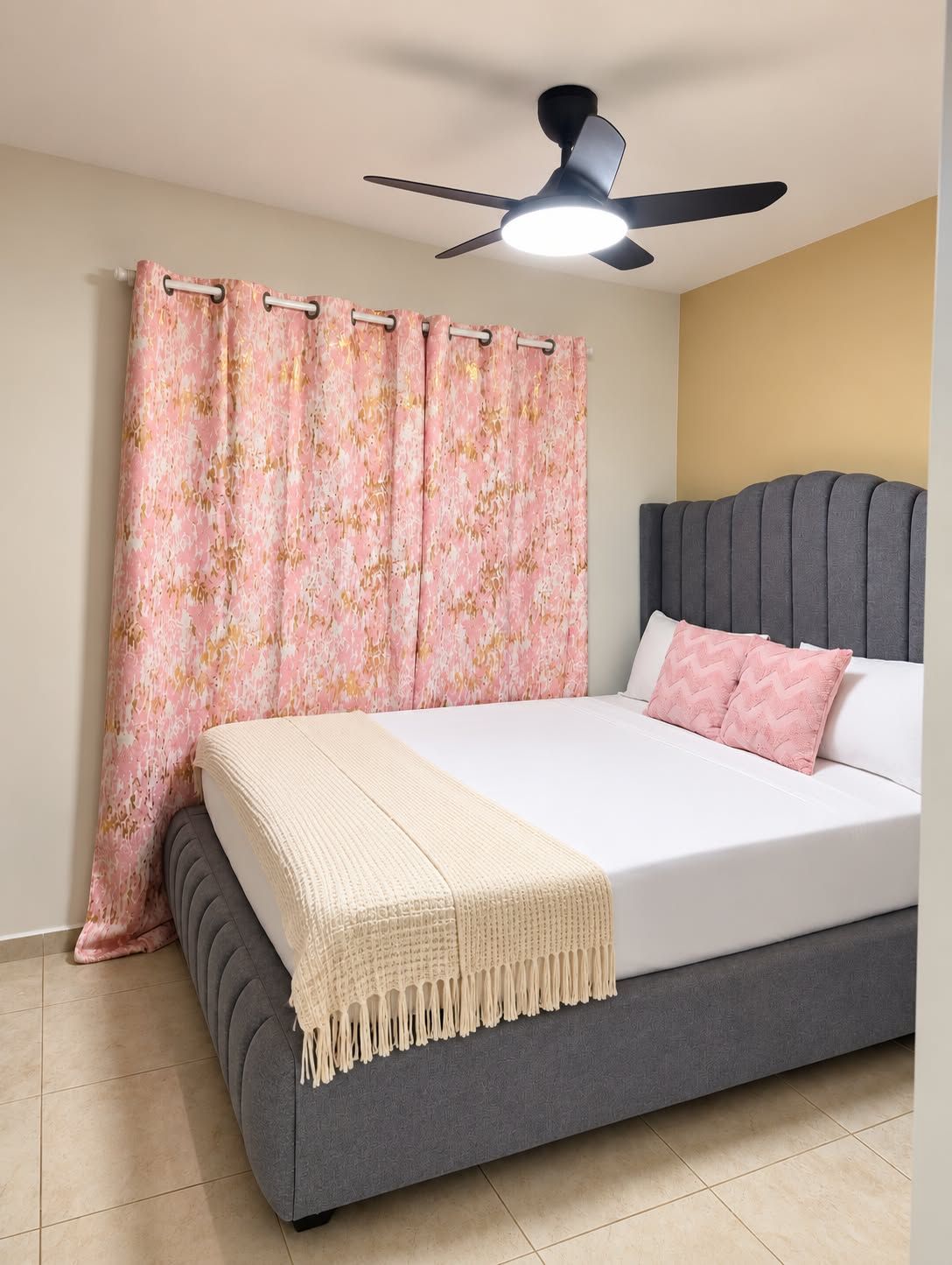 Quarto com cama, ventilador de teto e cortinas.