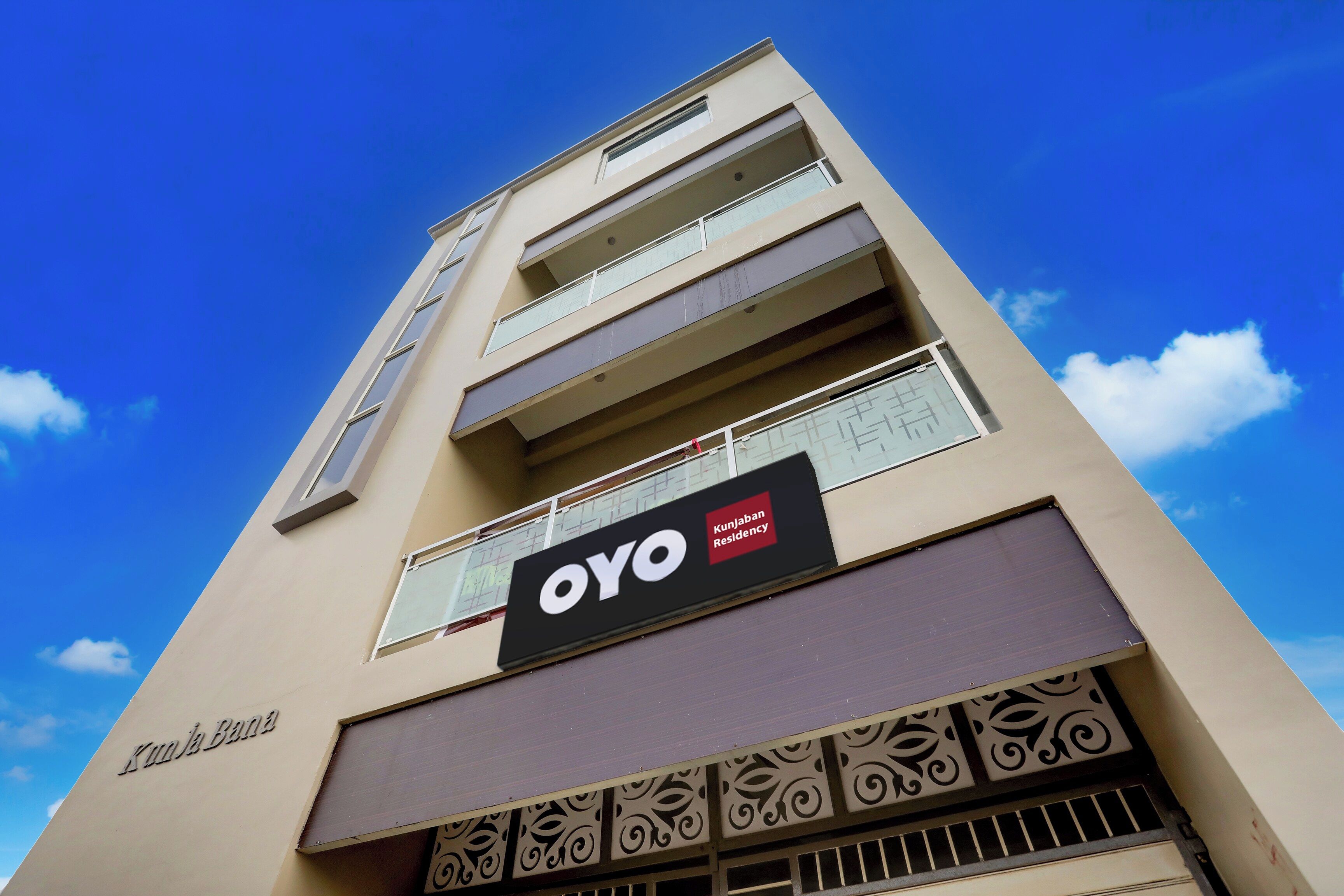 Um edifício de vários andares com varandas e uma placa com a inscrição 'OYO Kunjaban Residency'.