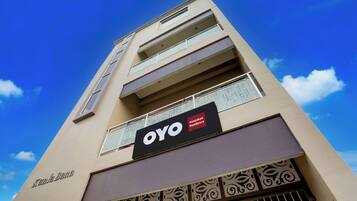 Um edifício de vários andares com varandas e uma placa com a inscrição 'OYO Kunjaban Residency'.