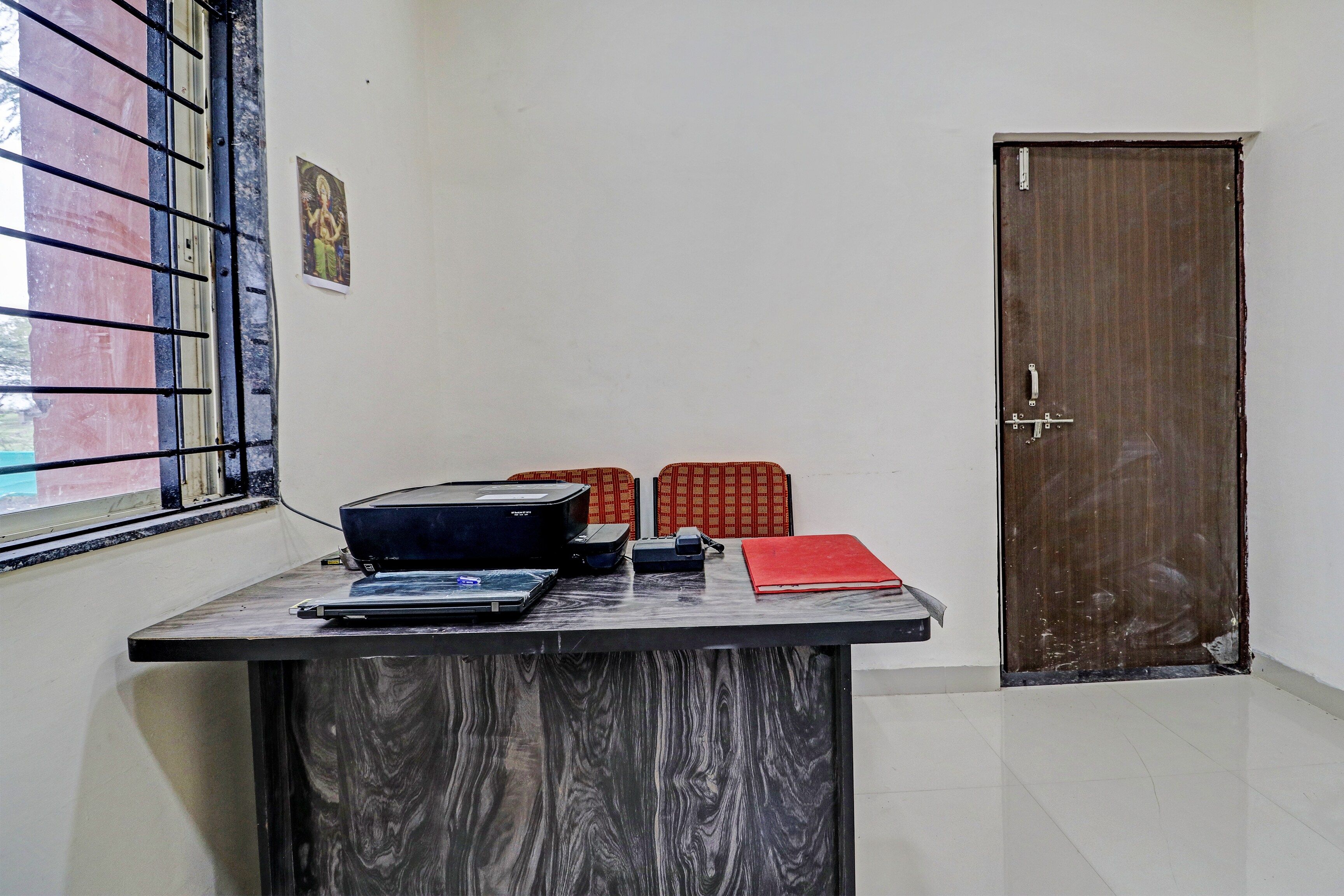 Quarto com escrivaninha, porta e janela com grades.