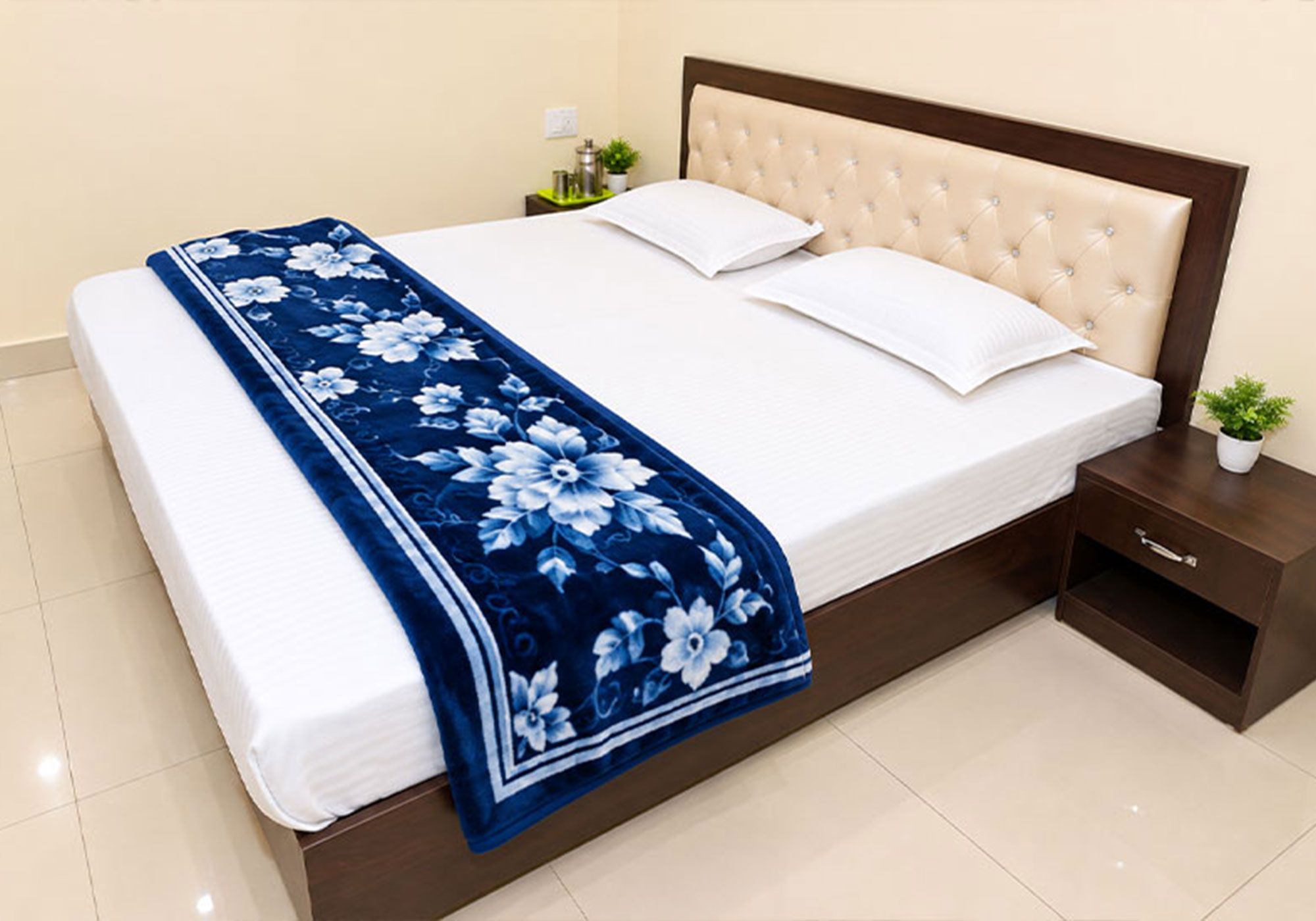Cama bem arrumada com colchão branco e colcha florida azul.