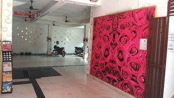 Uma área de recepção com um painel floral vermelho, ventiladores de teto e motocicletas estacionadas.