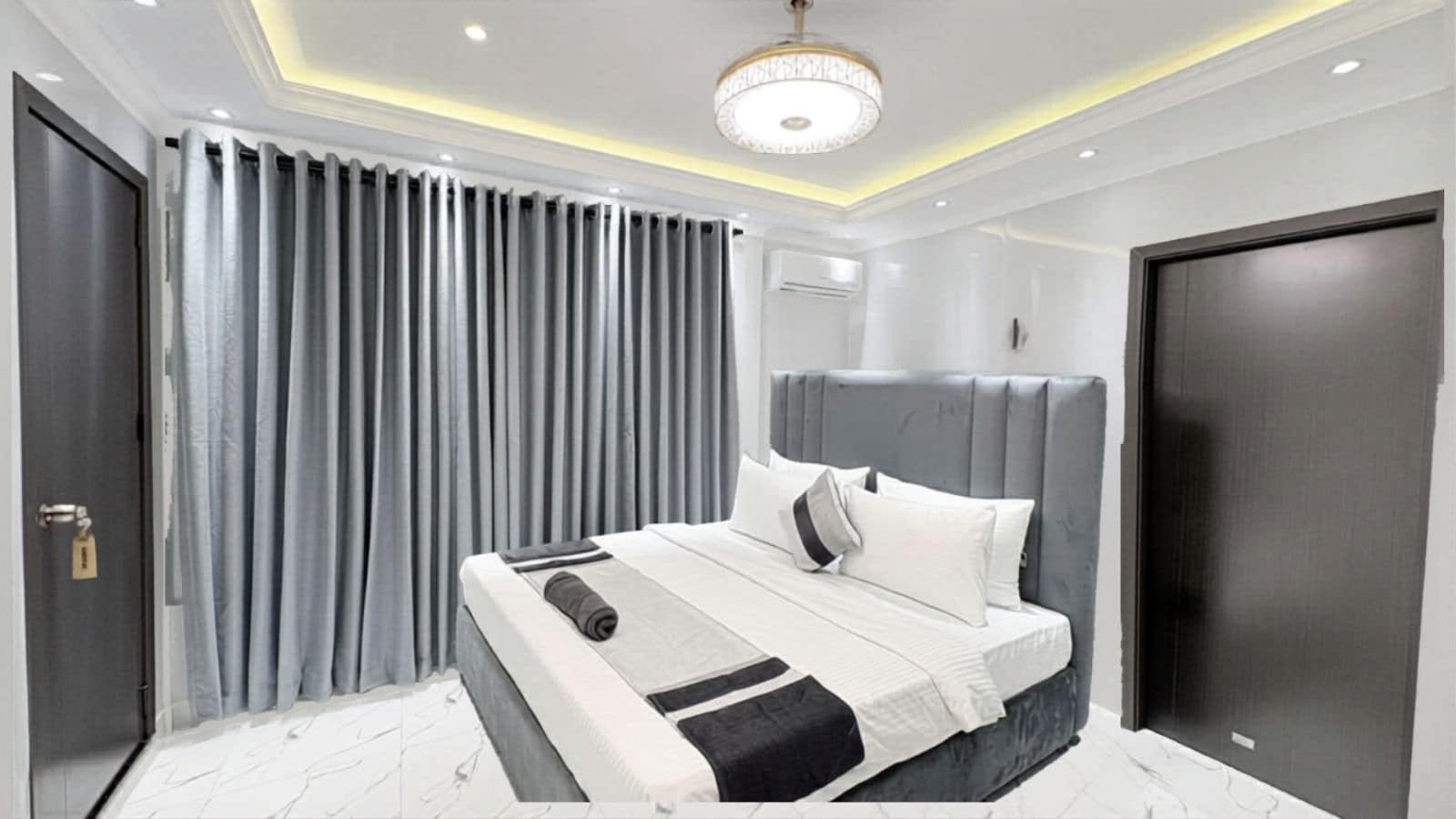 Quarto moderno com uma cama grande, cabeceira e luminária no teto.