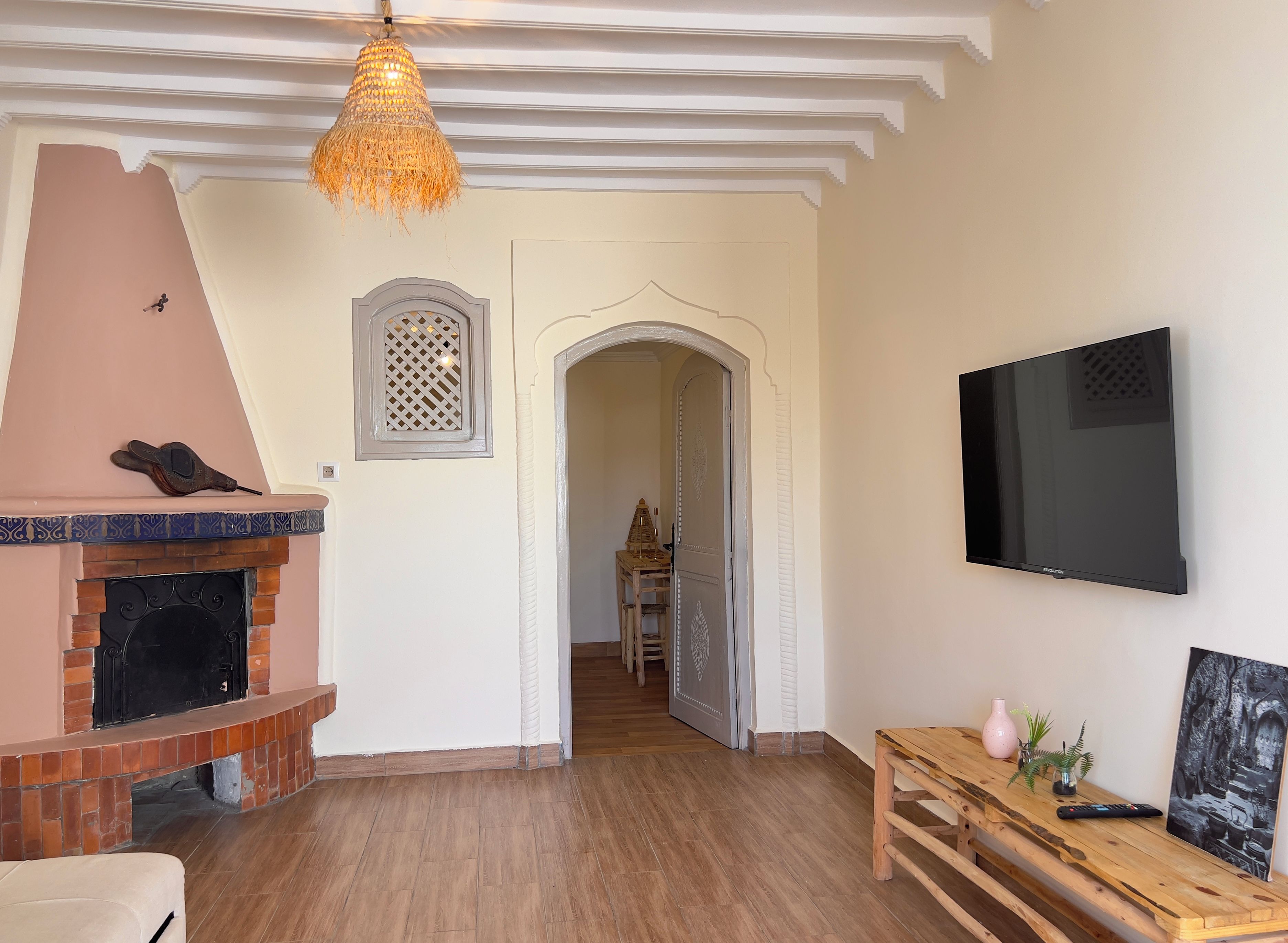 Sala de estar com lareira, televisão e um banco de madeira.