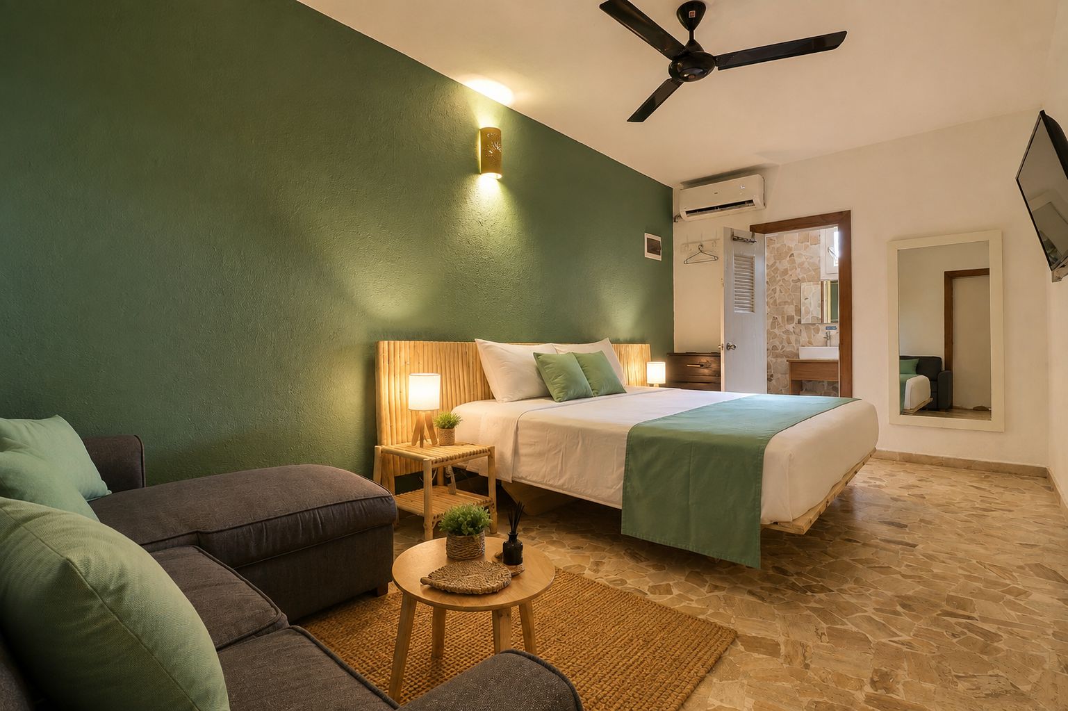 Quarto com cama, mesa de cabeceira, abajur, ventilador de teto e piso de pedra.