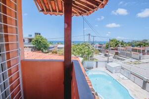 Varanda residencial com vista para uma piscina e o mar.