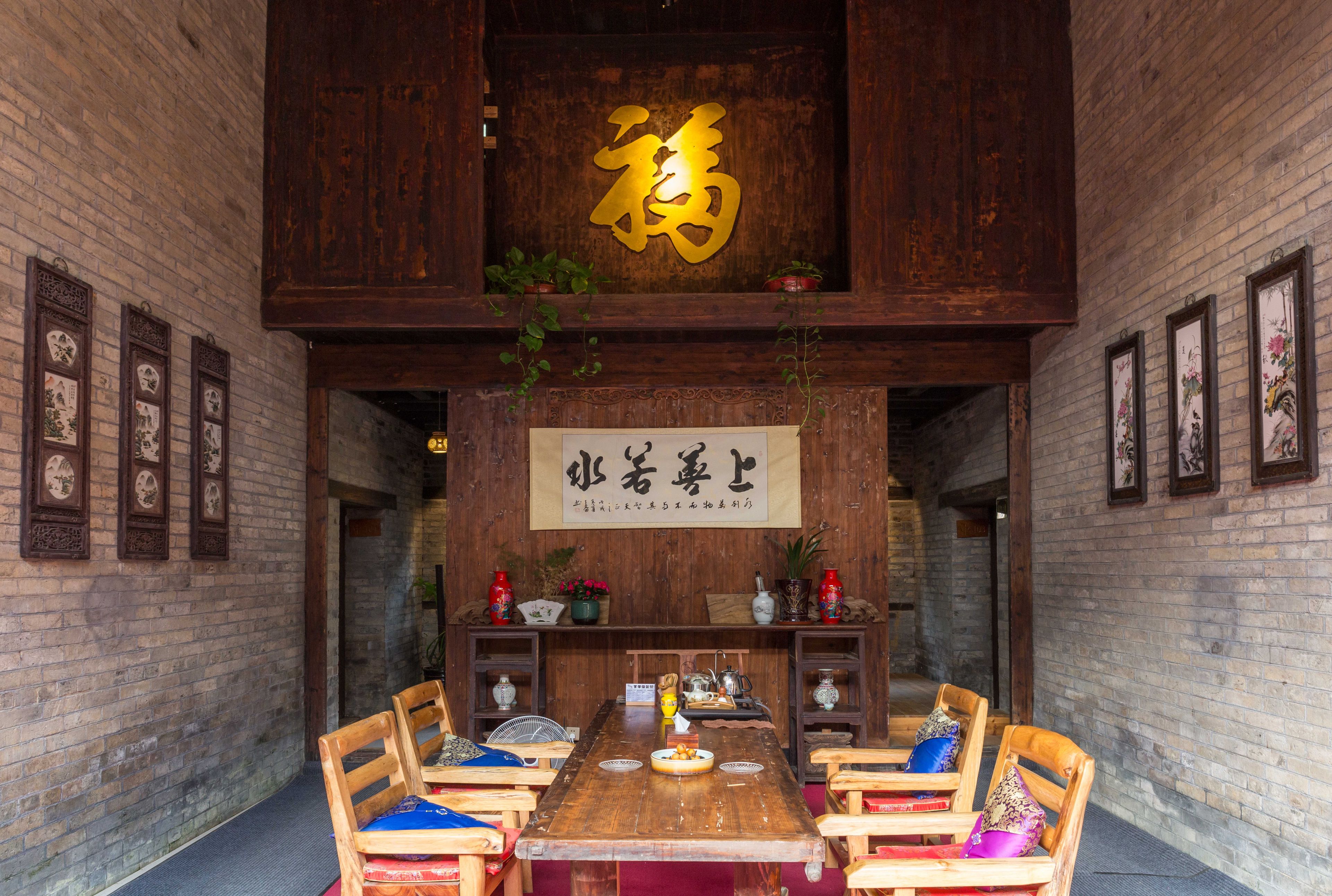 Uma sala de jantar tradicional chinesa com uma mesa de madeira, cadeiras e um letreiro pendurado com caracteres chineses.