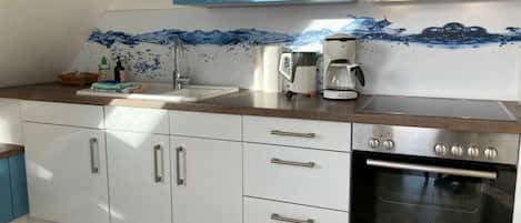 Cozinha moderna com armários brancos, forno Bosch e cafeteira no balcão.