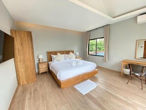 Quarto com cama grande, mesas de cabeceira, escrivaninha e uma cadeira.