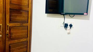 Uma porta de madeira e uma televisão fixada numa parede branca.