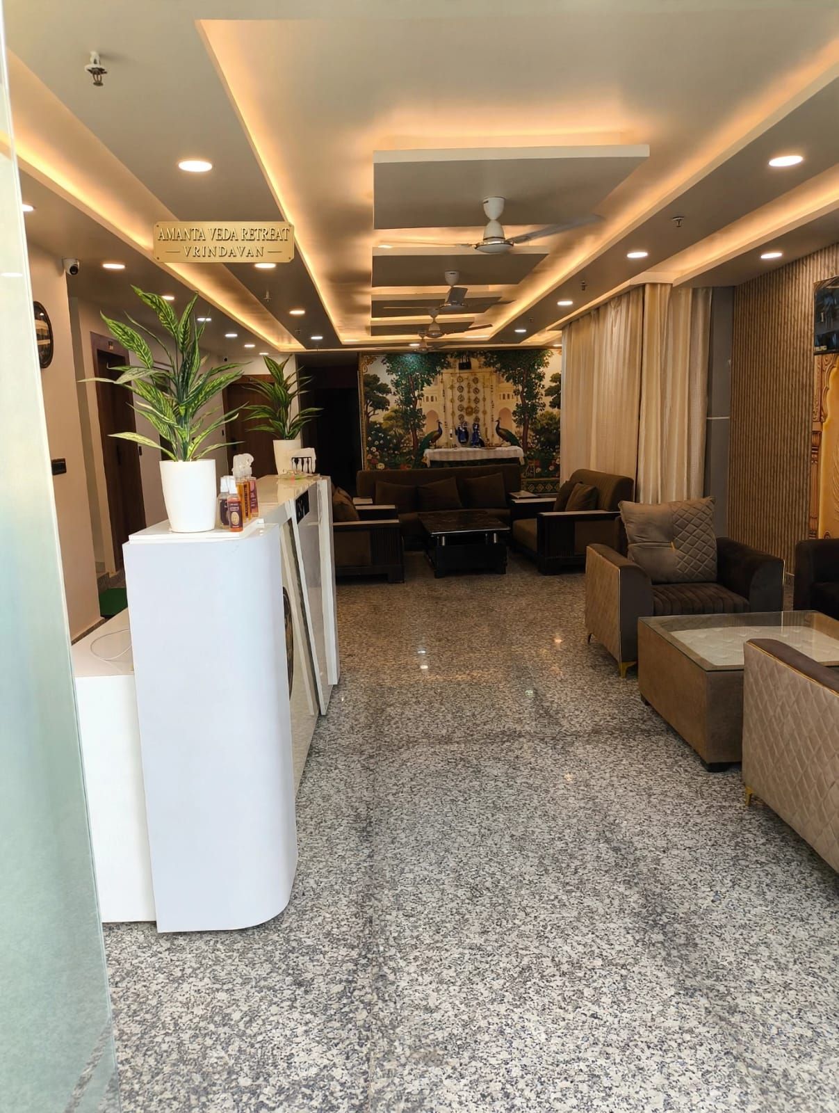 Um saguão de hotel com balcão de recepção, área de estar e uma parede decorativa.