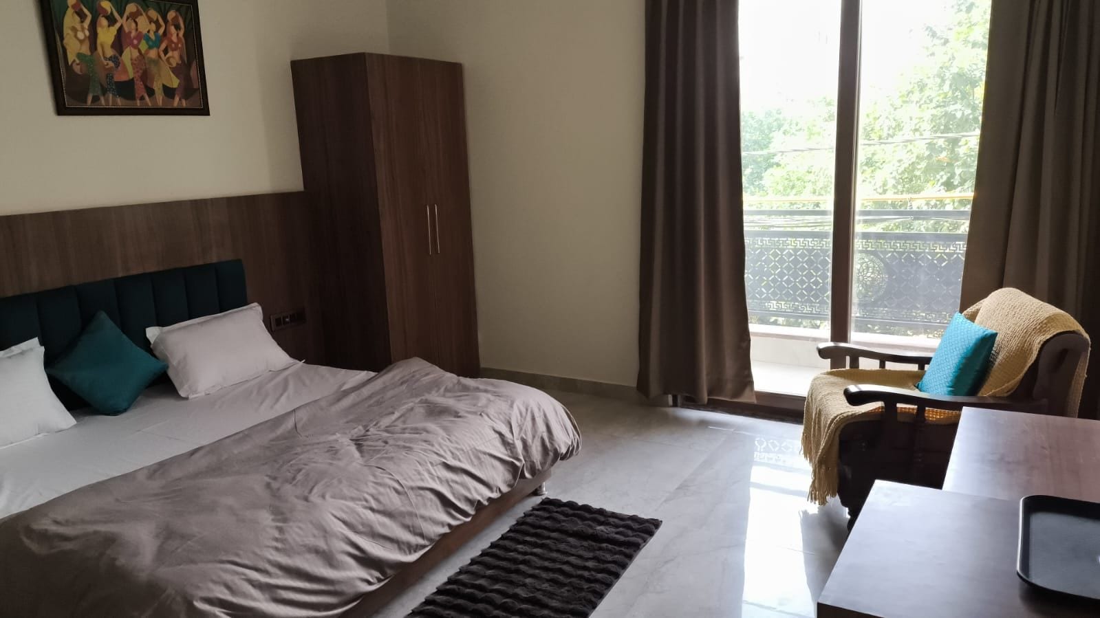 Quarto de hotel com cama, cadeira, guarda-roupa e janela com cortinas.