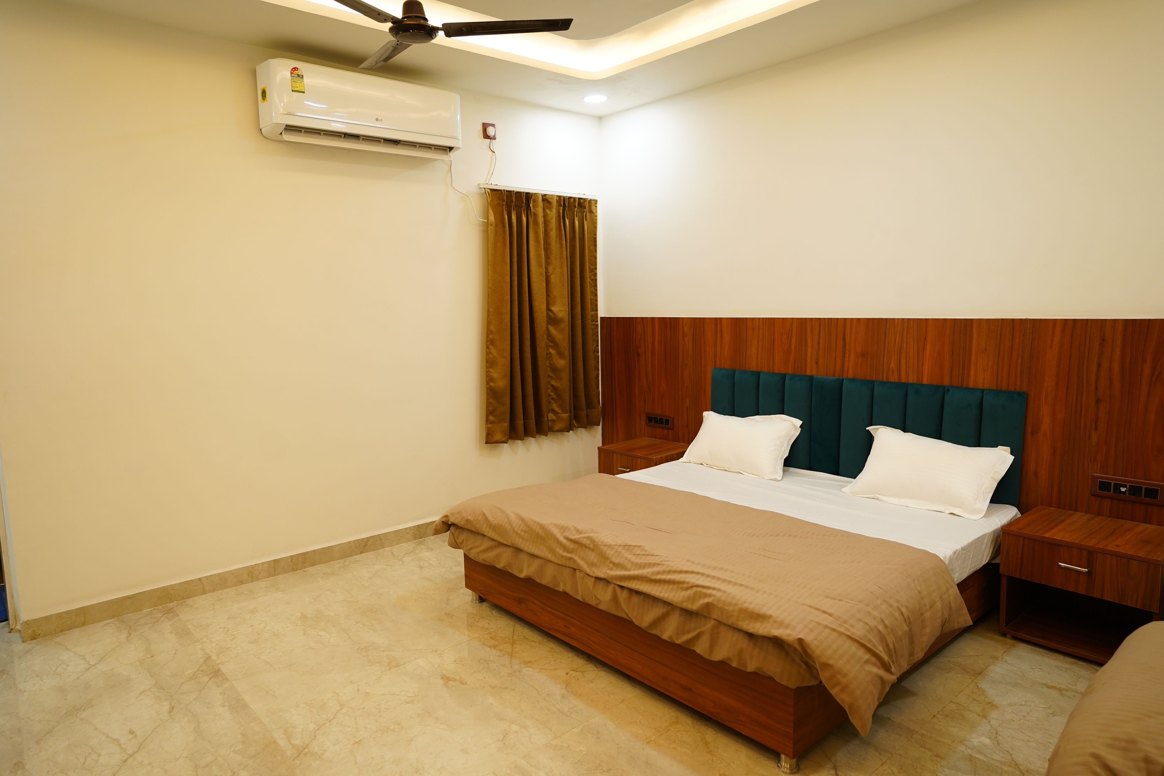 Quarto de hotel com cama, cabeceira de madeira, mesa de cabeceira e ar condicionado.